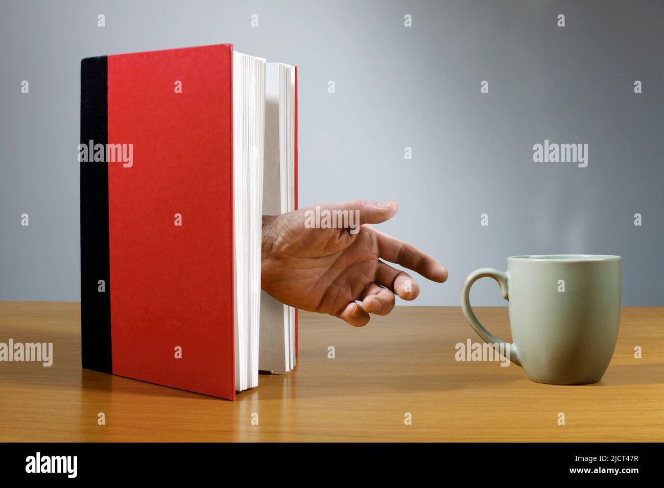 Open book with human hand reaching for coffee cup Stock Photo - Alamy
