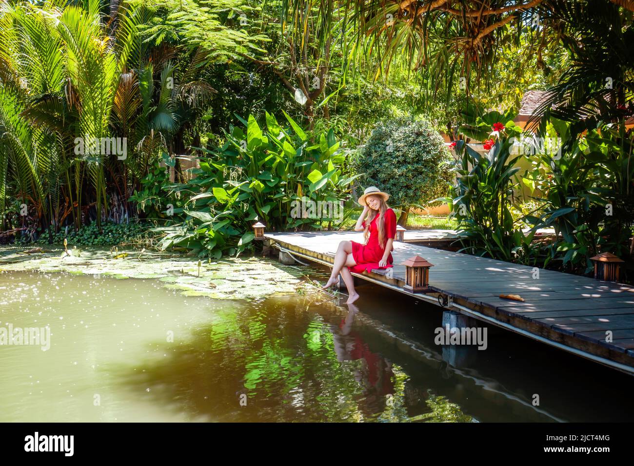 Travel woman in red dress relax in modern resort. Female traveler on ...