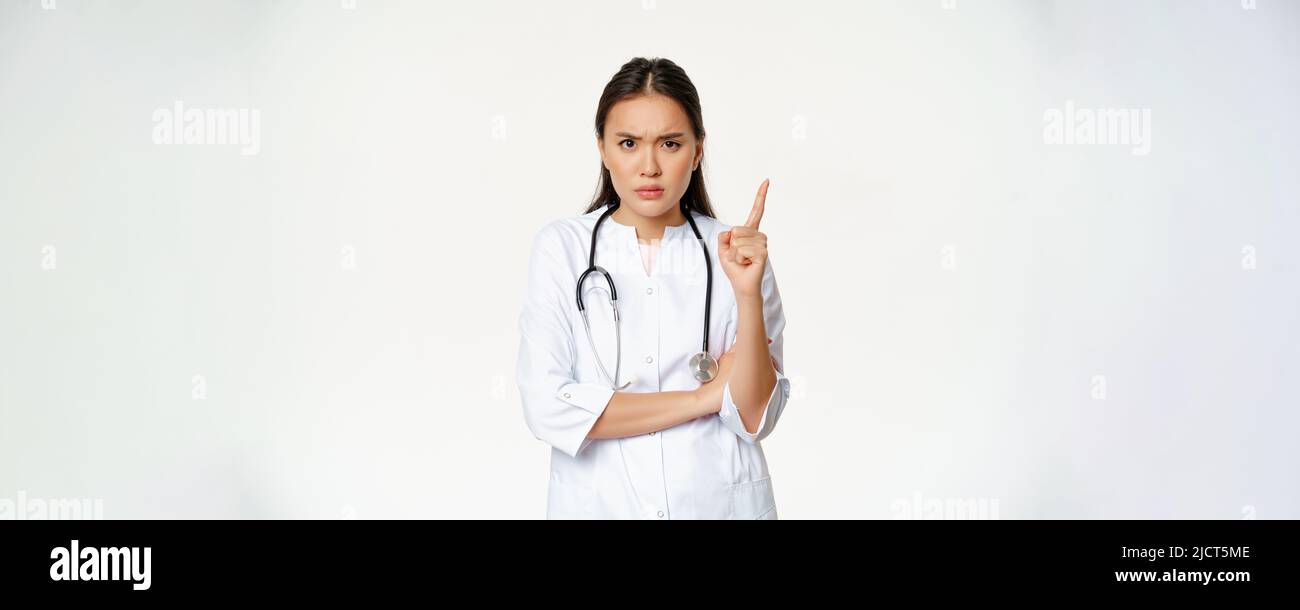 Doctor shows disapproval, scolding patient. Angry female asian ...