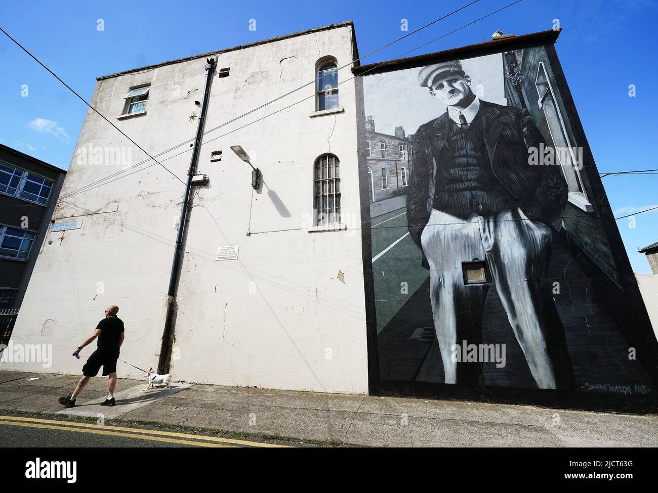 A man and a dog walk past a mural of James Joyce by Shane Sutton Art on ...