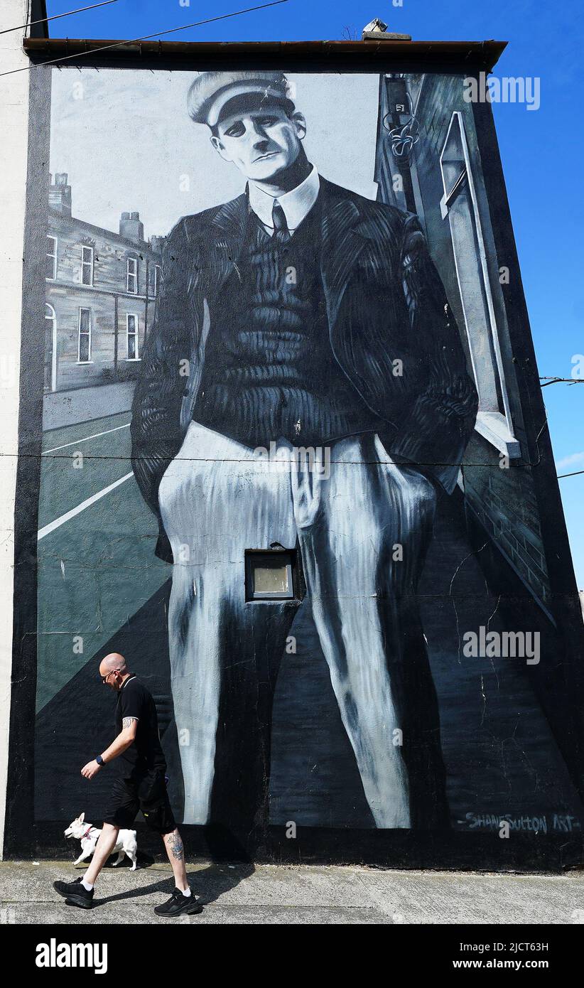 A man and a dog walk past a mural of James Joyce by Shane Sutton Art on ...
