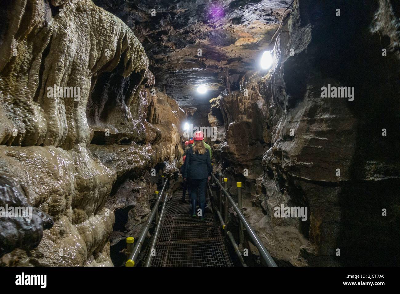 Visitors in hard hats on a walkway inside the stunning White Scar Caves ...