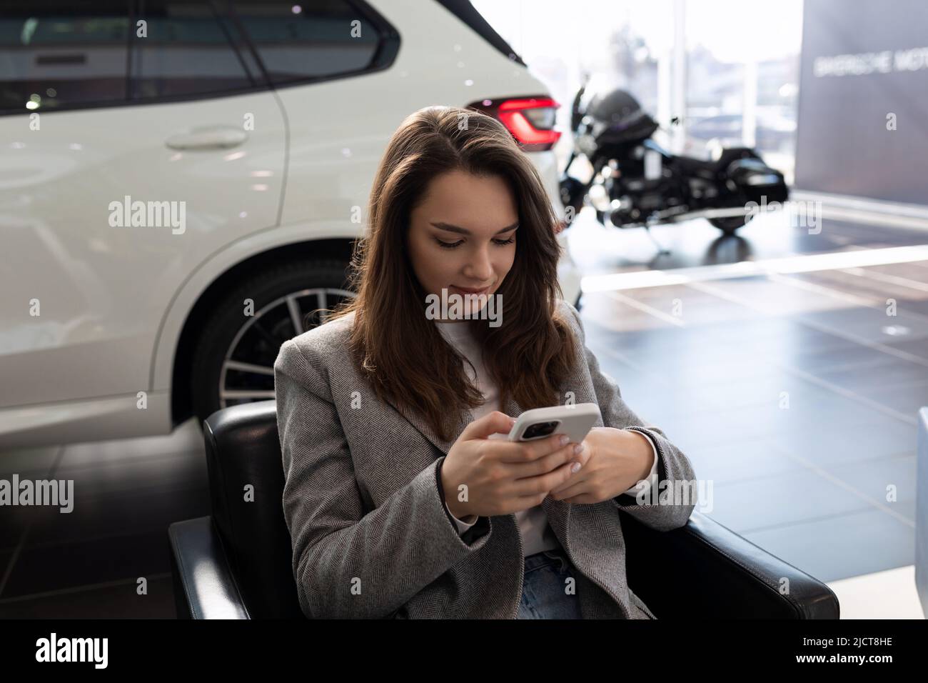 woman waiting to buy a new car in a car dealership at the reception ...