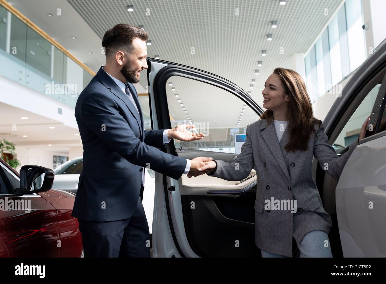 car dealership employee helps a young woman with a choice of a new car ...