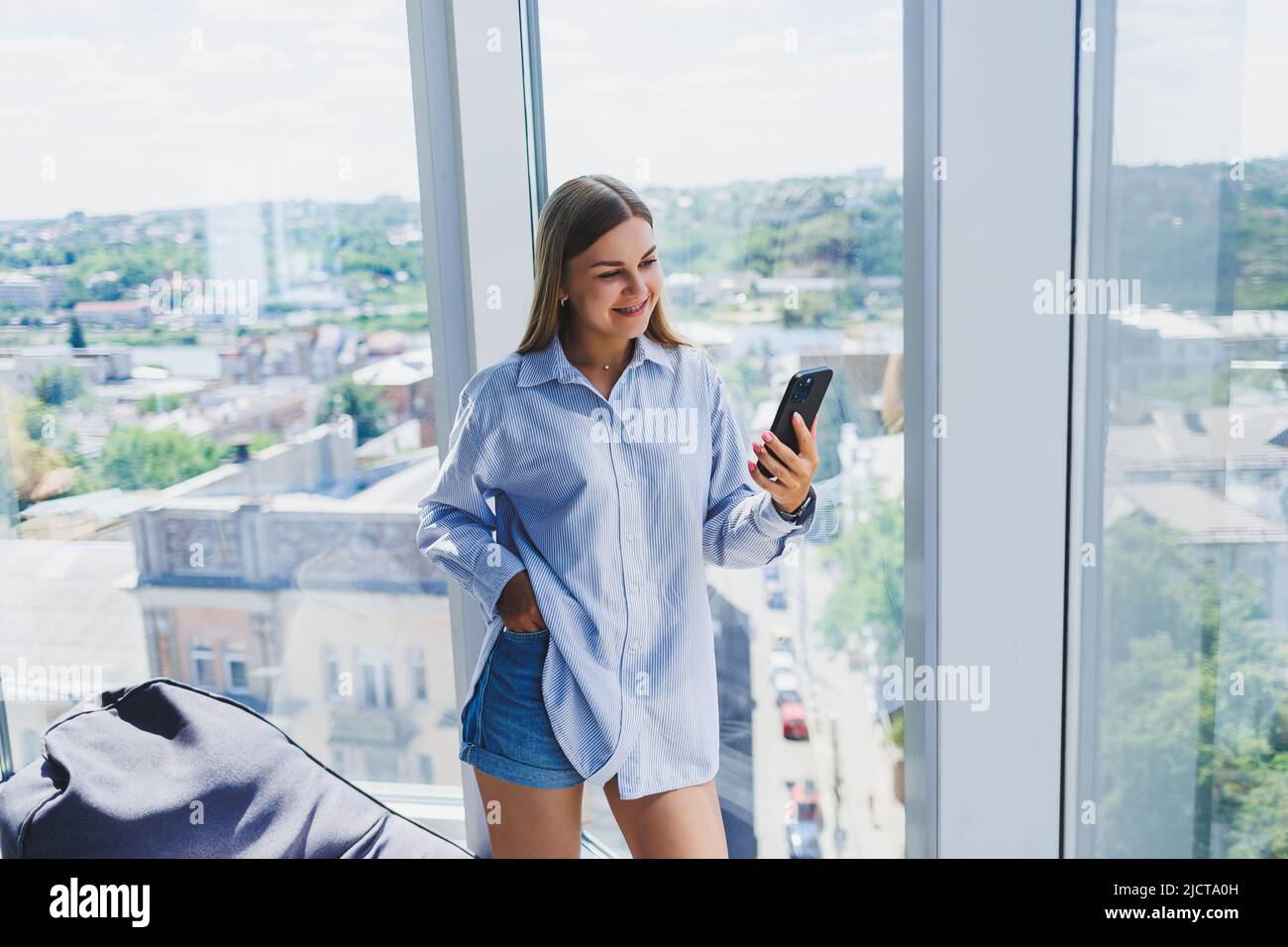 Attractive female blogger with a modern smartphone in her hands stands ...