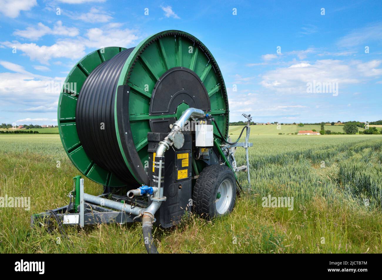 Agricultural irrigation system with a big hose reel in front of a wheat ...