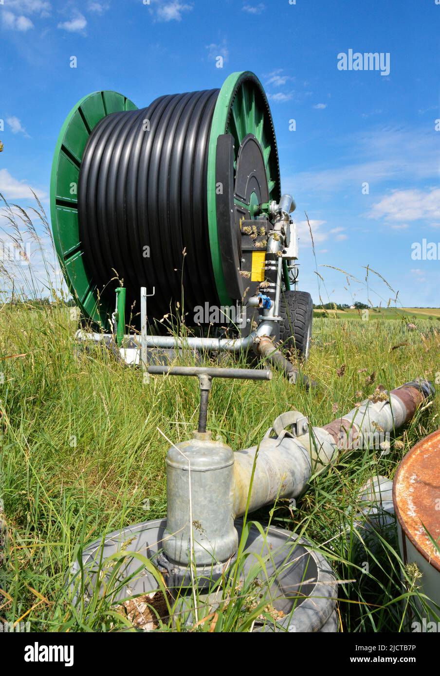 Agricultural irrigation system with a big hose reel in front of a wheat ...