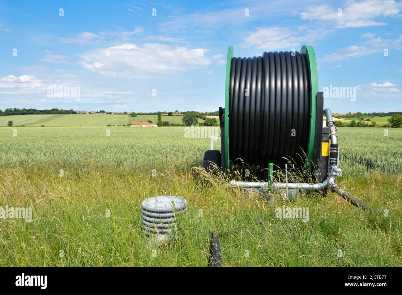 Agricultural irrigation system with a big hose reel in front of a wheat ...