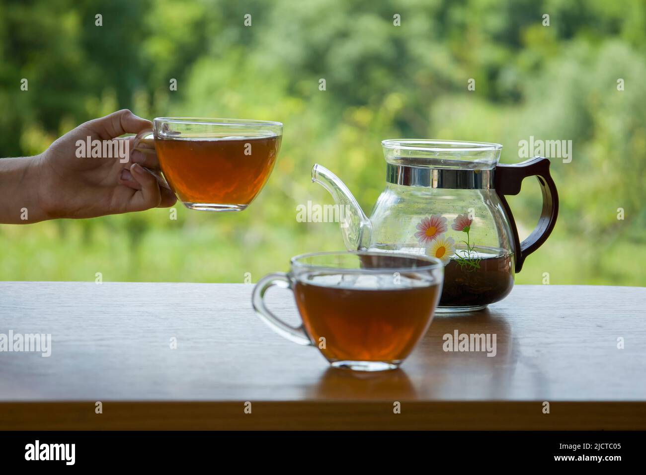 Teapot with a transparent cup of tea in nature Stock Photo - Alamy