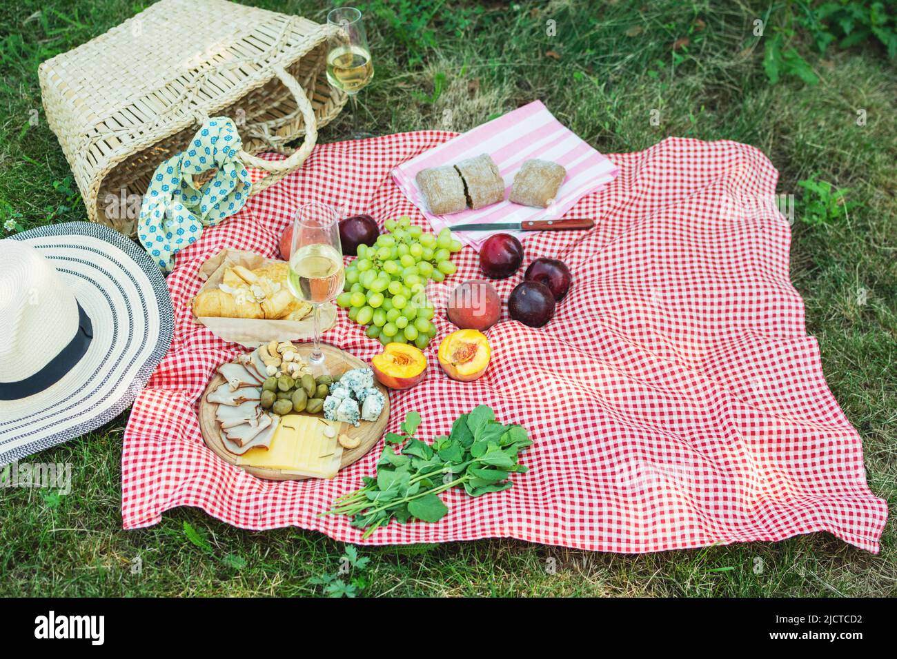 Summer picnic in the park on the grass. Wine, fruit and croissants ...