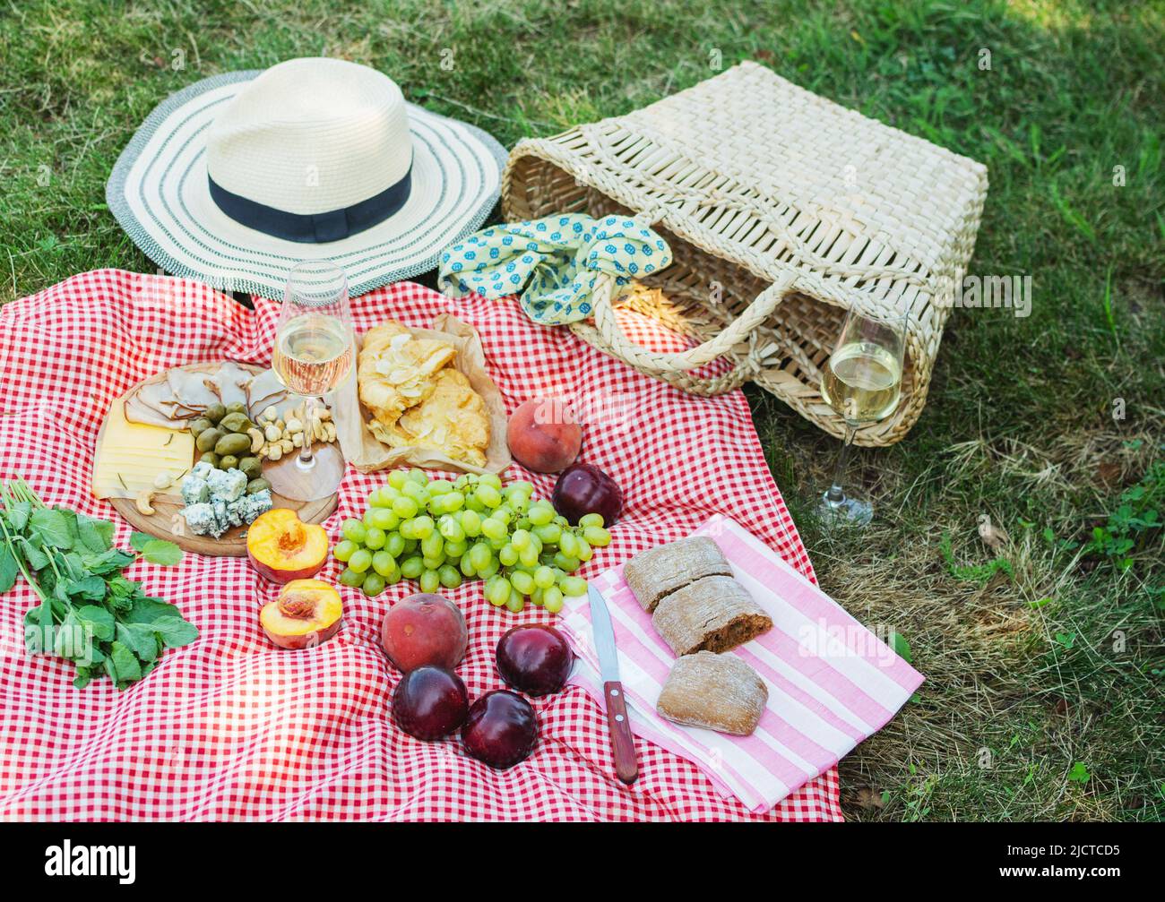 Summer picnic in the park on the grass. Wine, fruit and croissants ...