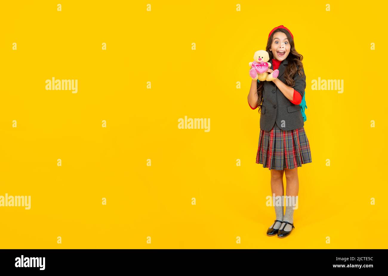 amazed child in school uniform with backpack and toy on yellow ...