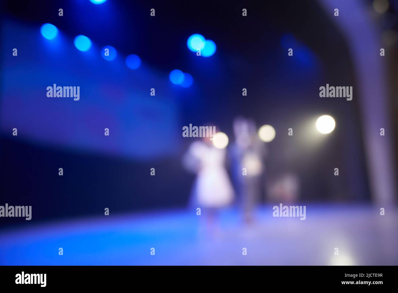 Blurry background of a dance scene with a girl in a white dress. Bright ...