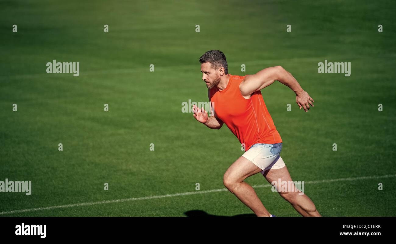 energetic athletic muscular man runner running outdoor on green grass ...