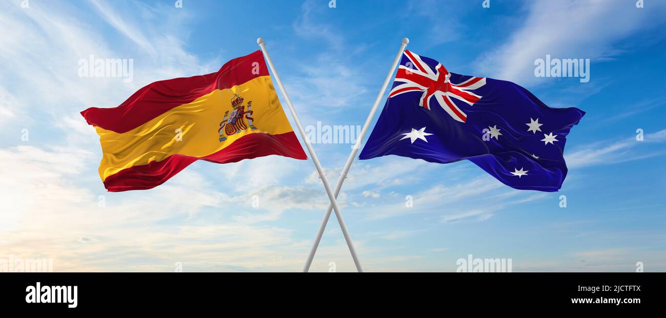 two crossed flags Spane and Australia waving in wind at cloudy sky ...