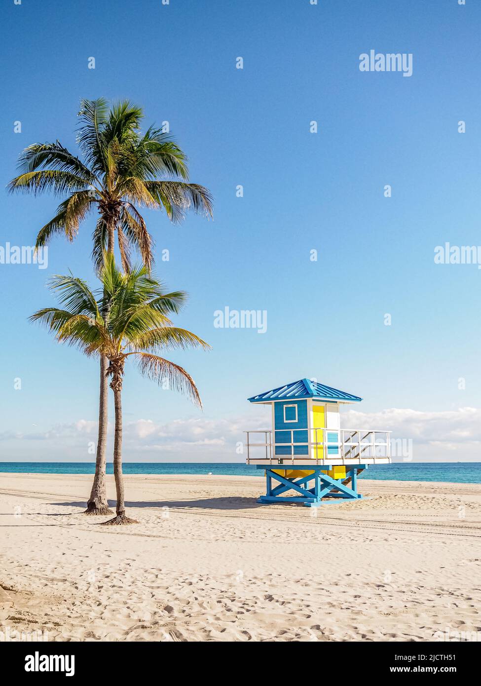 Colorful blue and yellow lifeguard station on beach with palm trees and ...