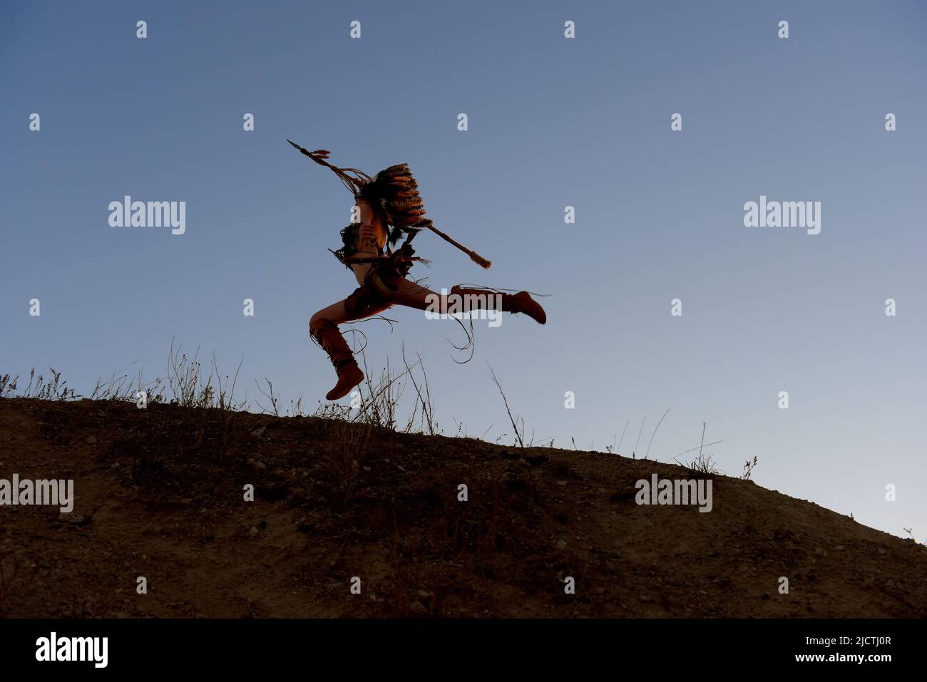 A young girl is silhouetted as native American Indian. She is seen ...