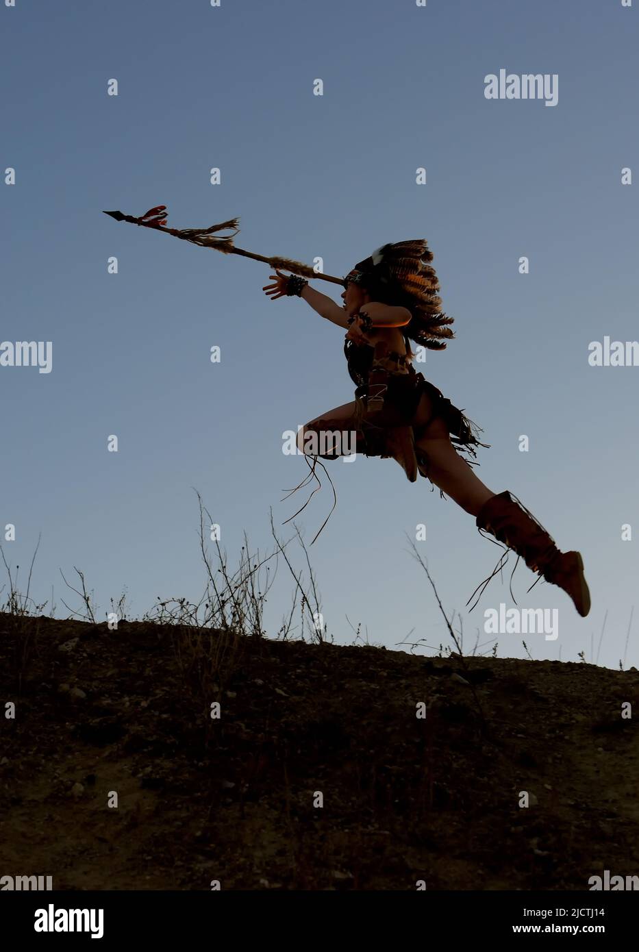 A young girl is silhouetted as native American Indian. She is seen ...