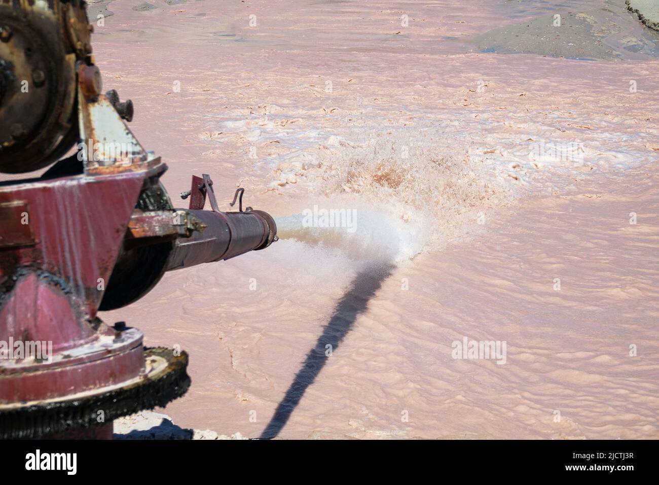 Foamy muddy water gushes out of the pipe under high pressure. Discharge ...