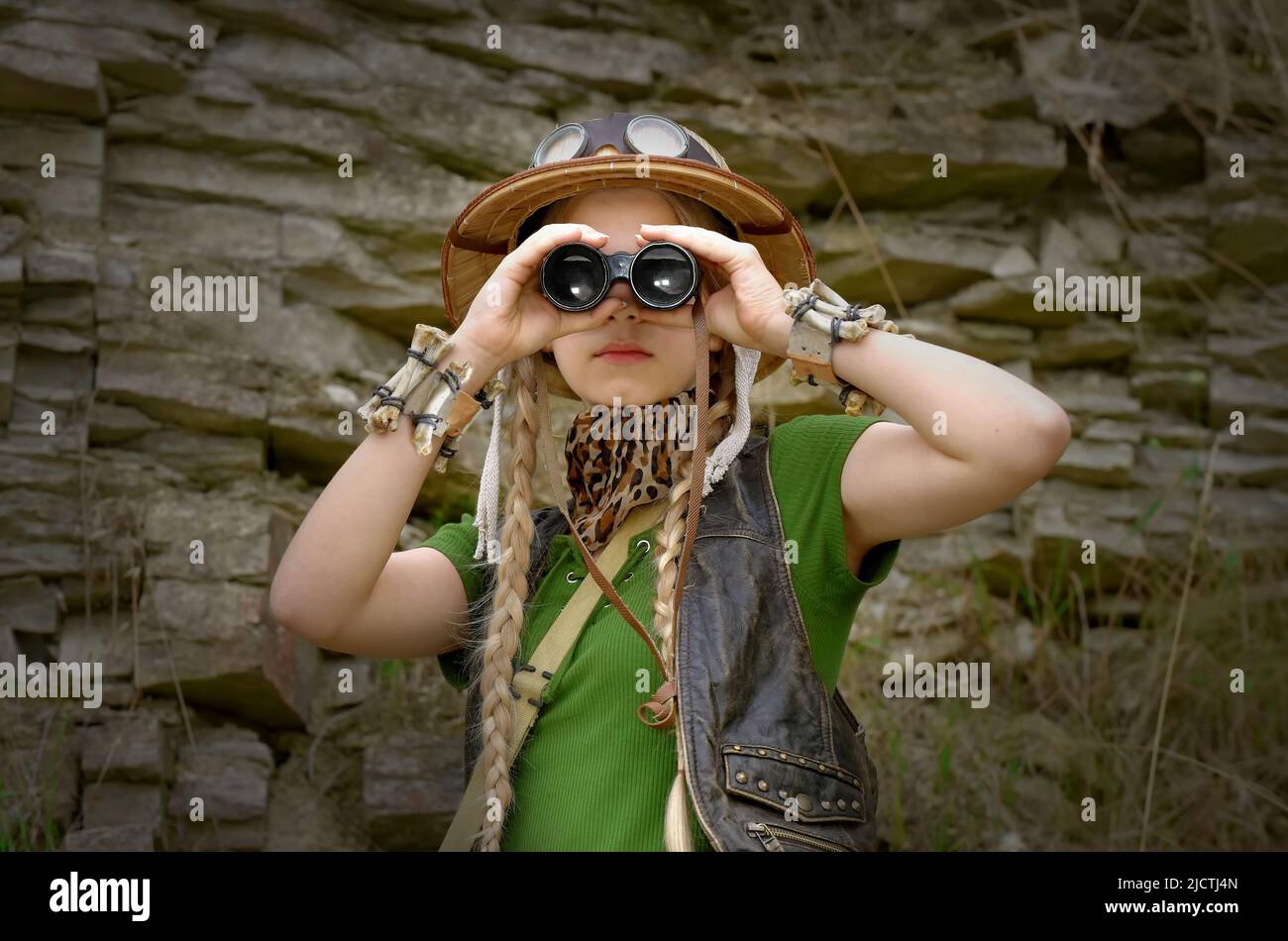 A young teenage explorer is seen standing in front of a rock wall. She ...
