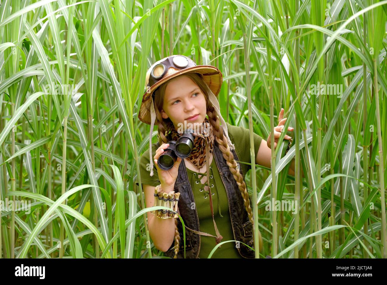 A young teenage explorer is seen in tall grass. She holds a pair of ...