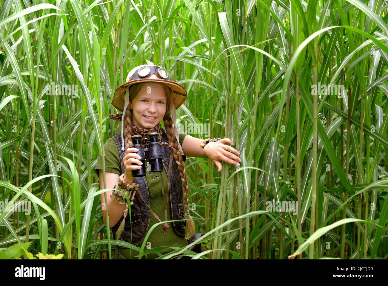 A young teenage explorer is seen in tall grass. She holds a pair of ...