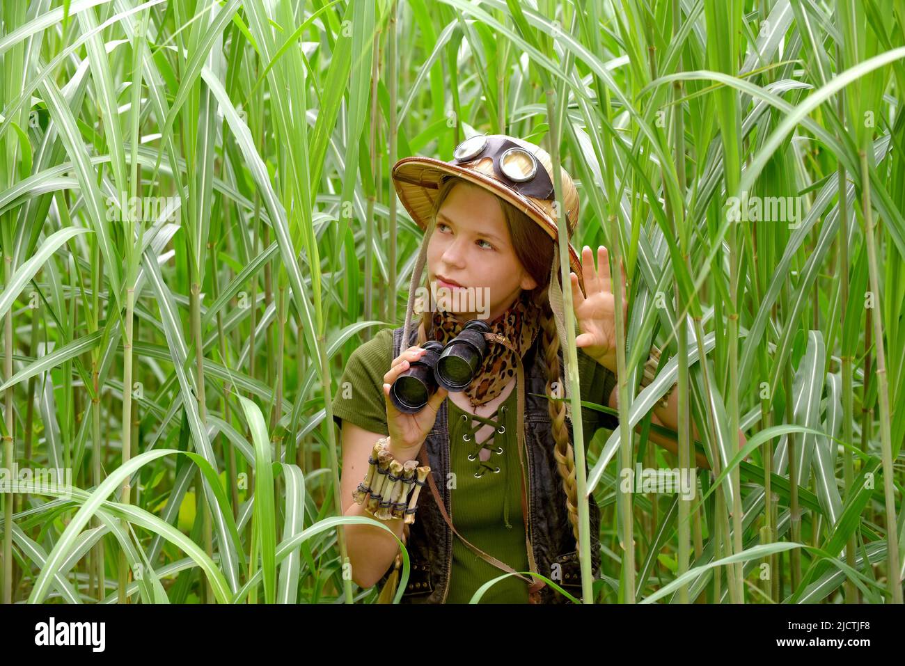 A young teenage explorer is seen in tall grass. She holds a pair of ...