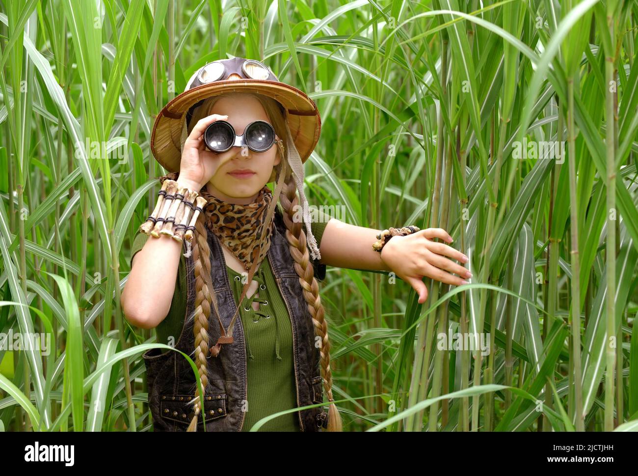A young teenage explorer is seen in tall grass. She holds a pair of ...