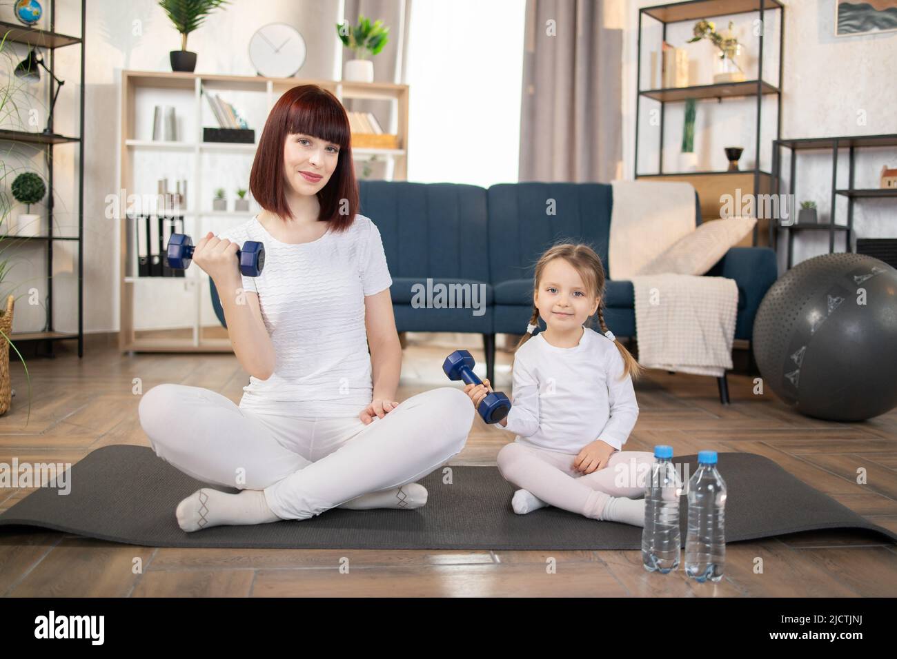 Sport, workout concept. Mom and Little Girl doing dumbbell exercises on ...