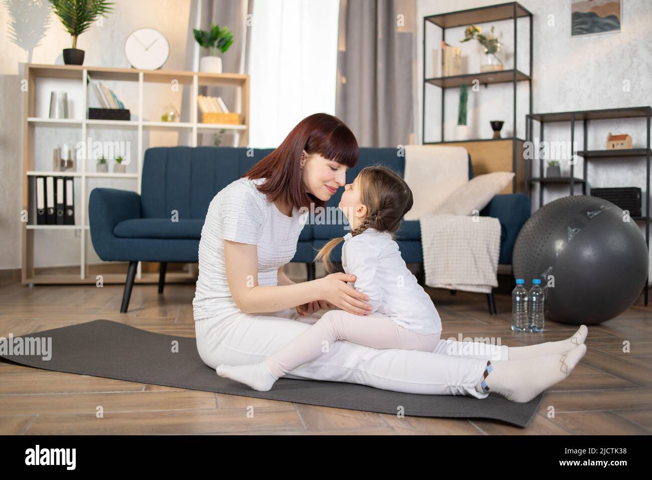 Portrait of beautiful young mother in white sports wear with her ...