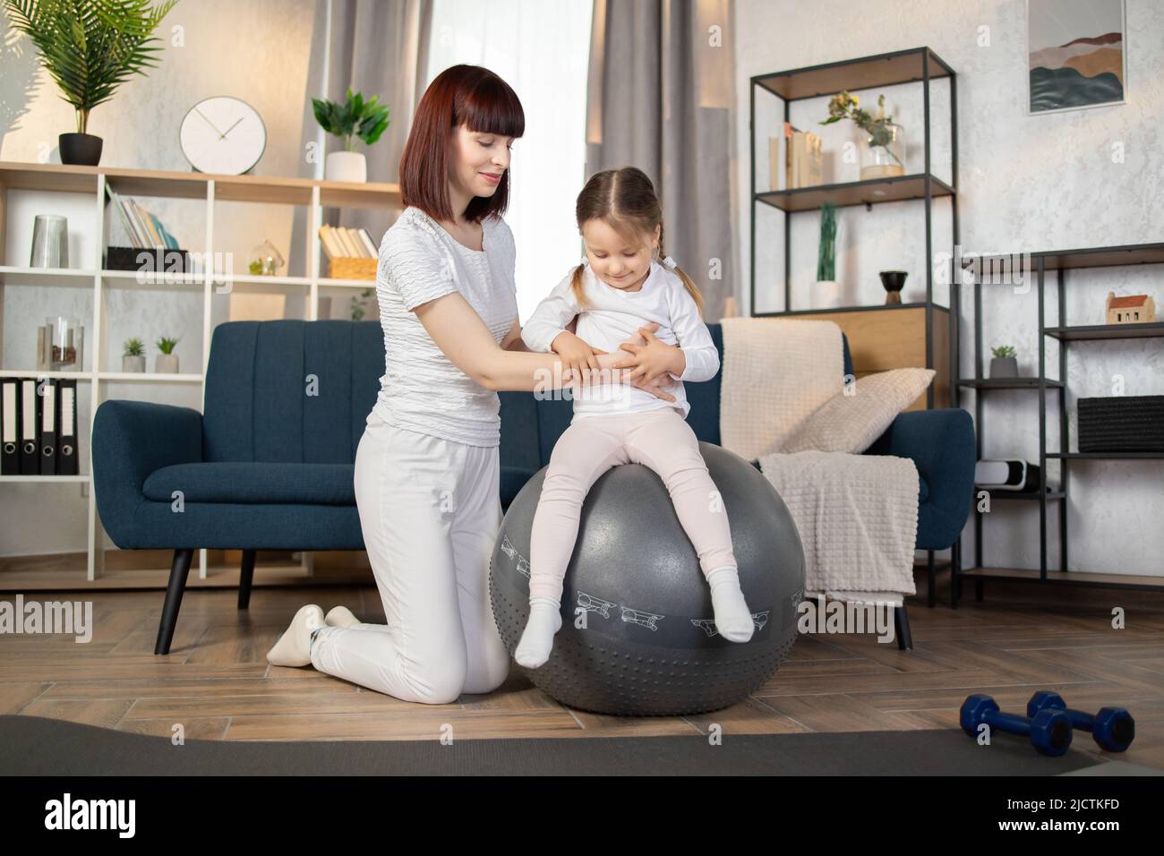 Happy fitness family training on swiss ball in living room. Portrait of ...