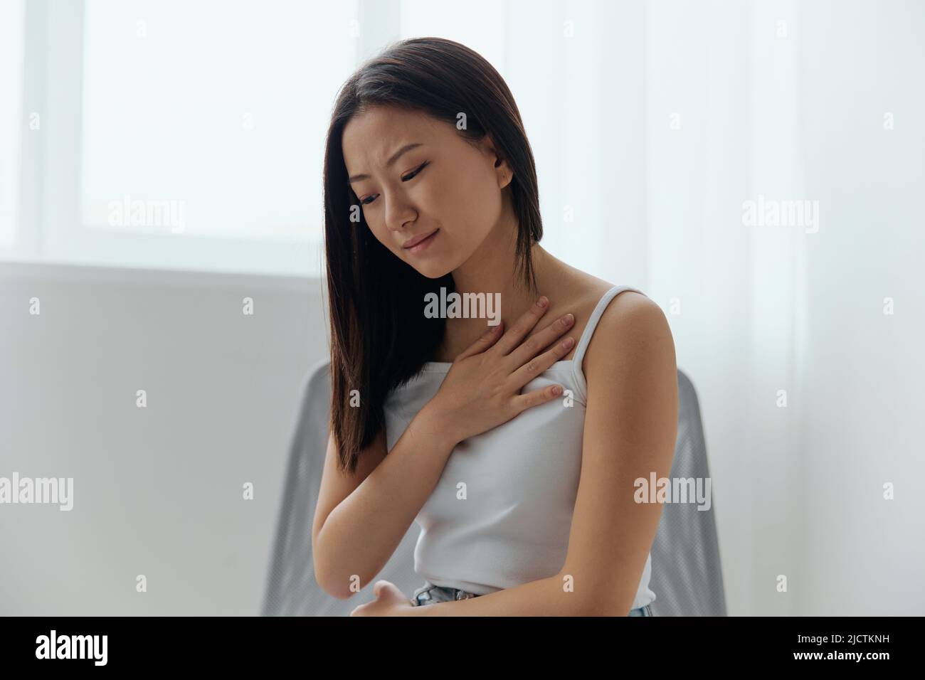 Heart attack. Suffering from pain tanned beautiful young Asian woman ...