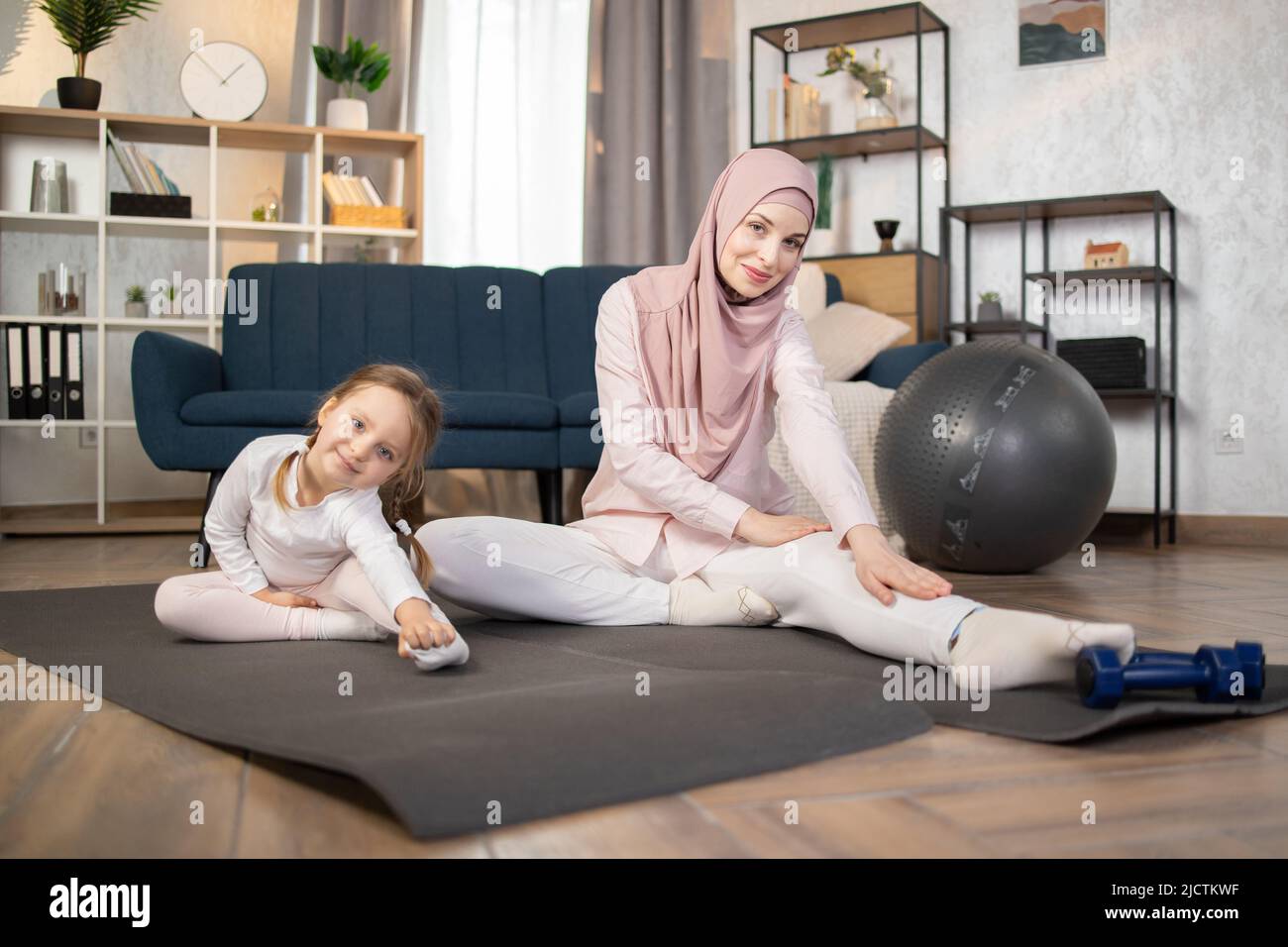 Young muslim mother in hijab showing her little daughter legs ...