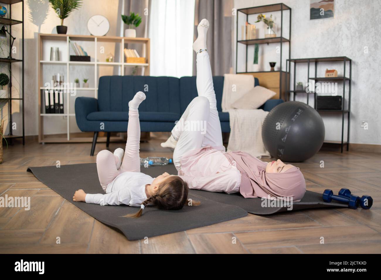 Young positive muslim woman doing stretching flexibility exercises ...
