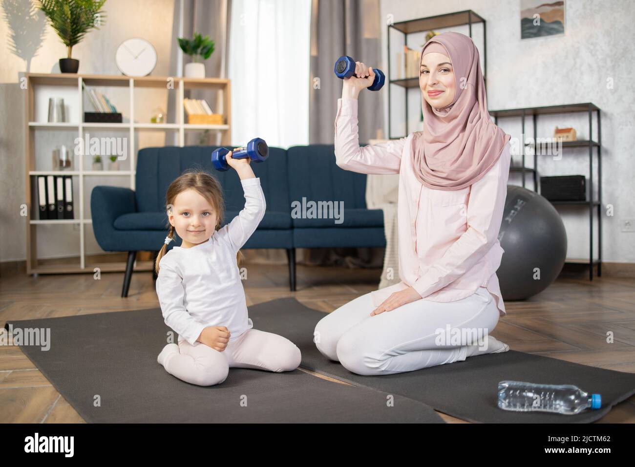 Young happy arab woman doing morning workout with her beautiful little ...