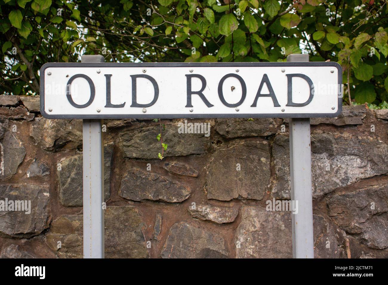 Old Road street name sign on two posts with an old stone wall in the ...