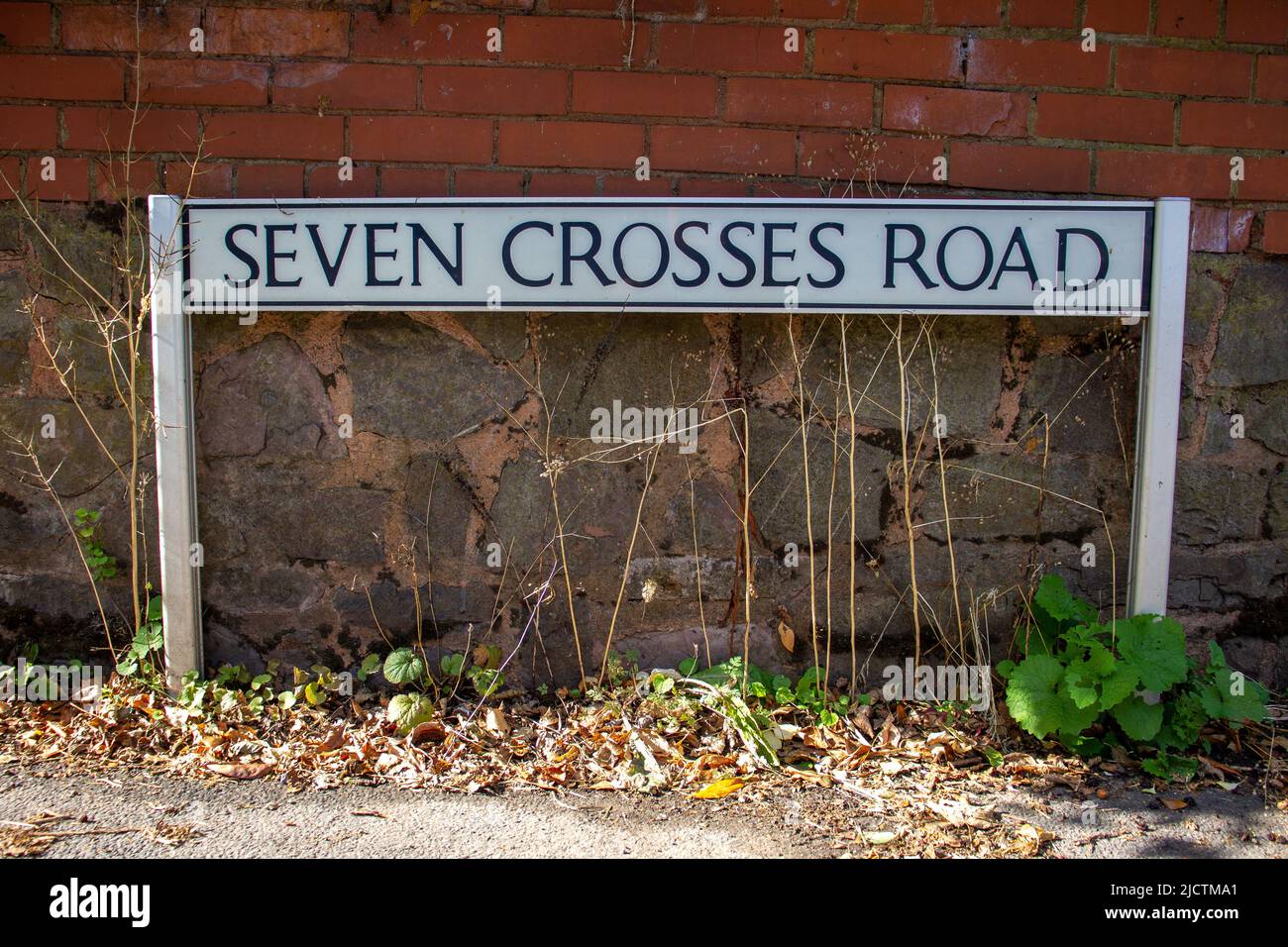 Seven Crosses Road street name sign on two posts with an old stone wall ...
