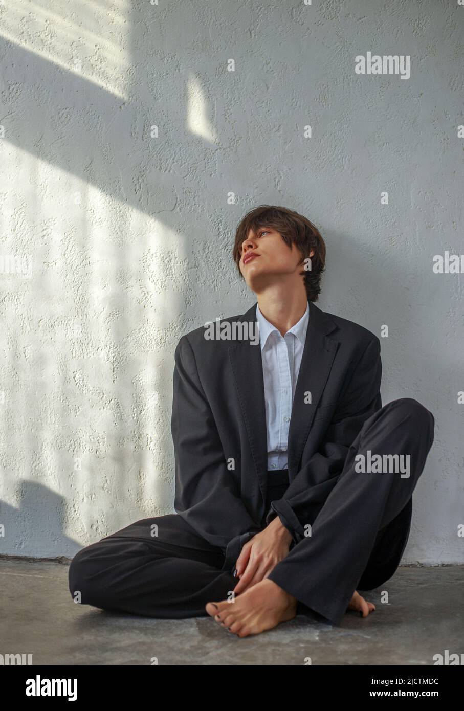 Young thoughtful and sad business woman on the background of a wall in ...