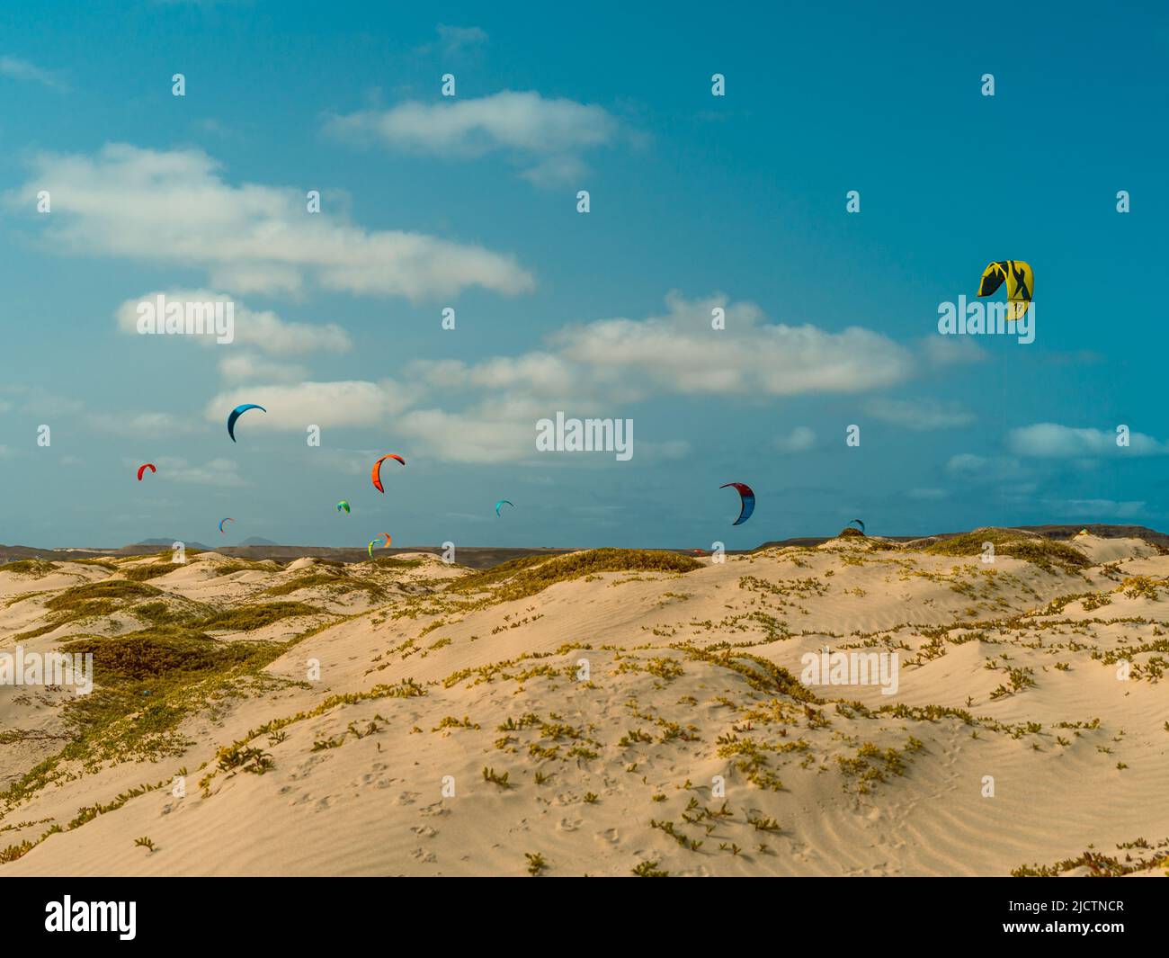 Kite surfers on horizon and dunes on foreground Stock Photo - Alamy