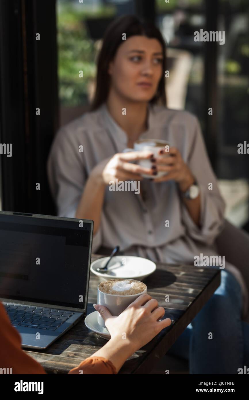 Two young business women in a cafe having one on one meeting. Friends ...