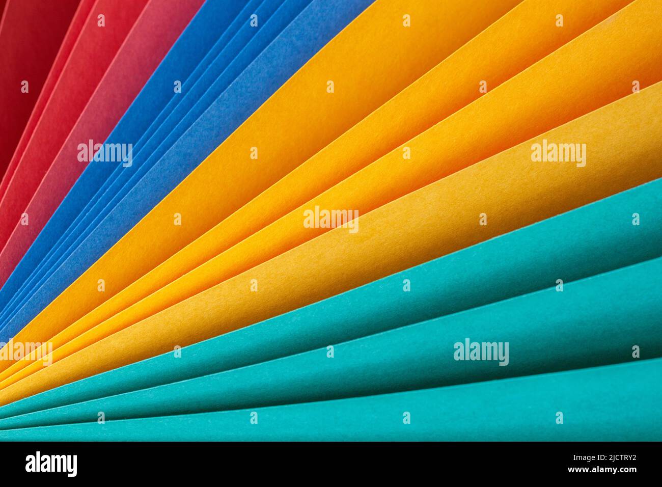 Multi-colored sheets of paper folded like rainbow fan close-up ...