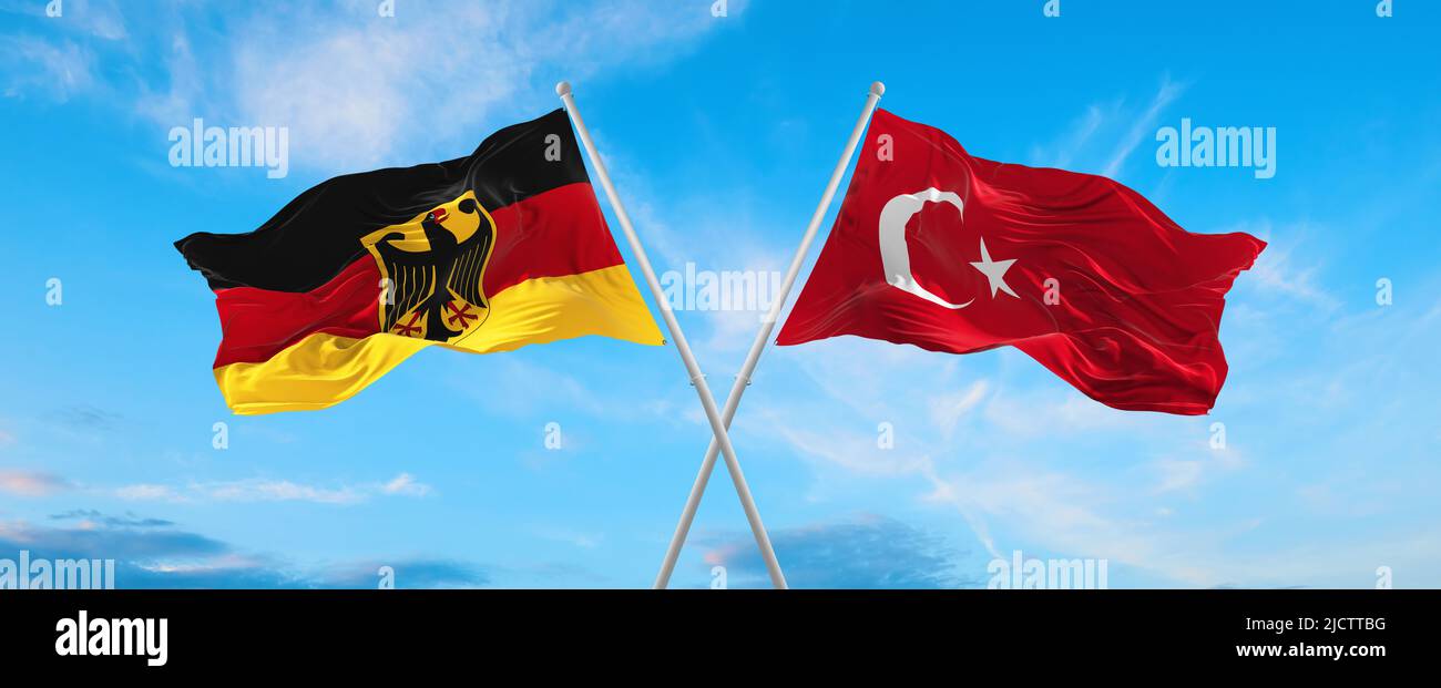 two crossed flags Germany and Turkey waving in wind at cloudy sky ...