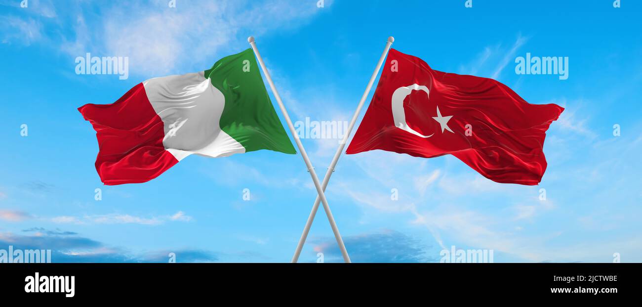 two crossed flags Italy and Turkey waving in wind at cloudy sky ...