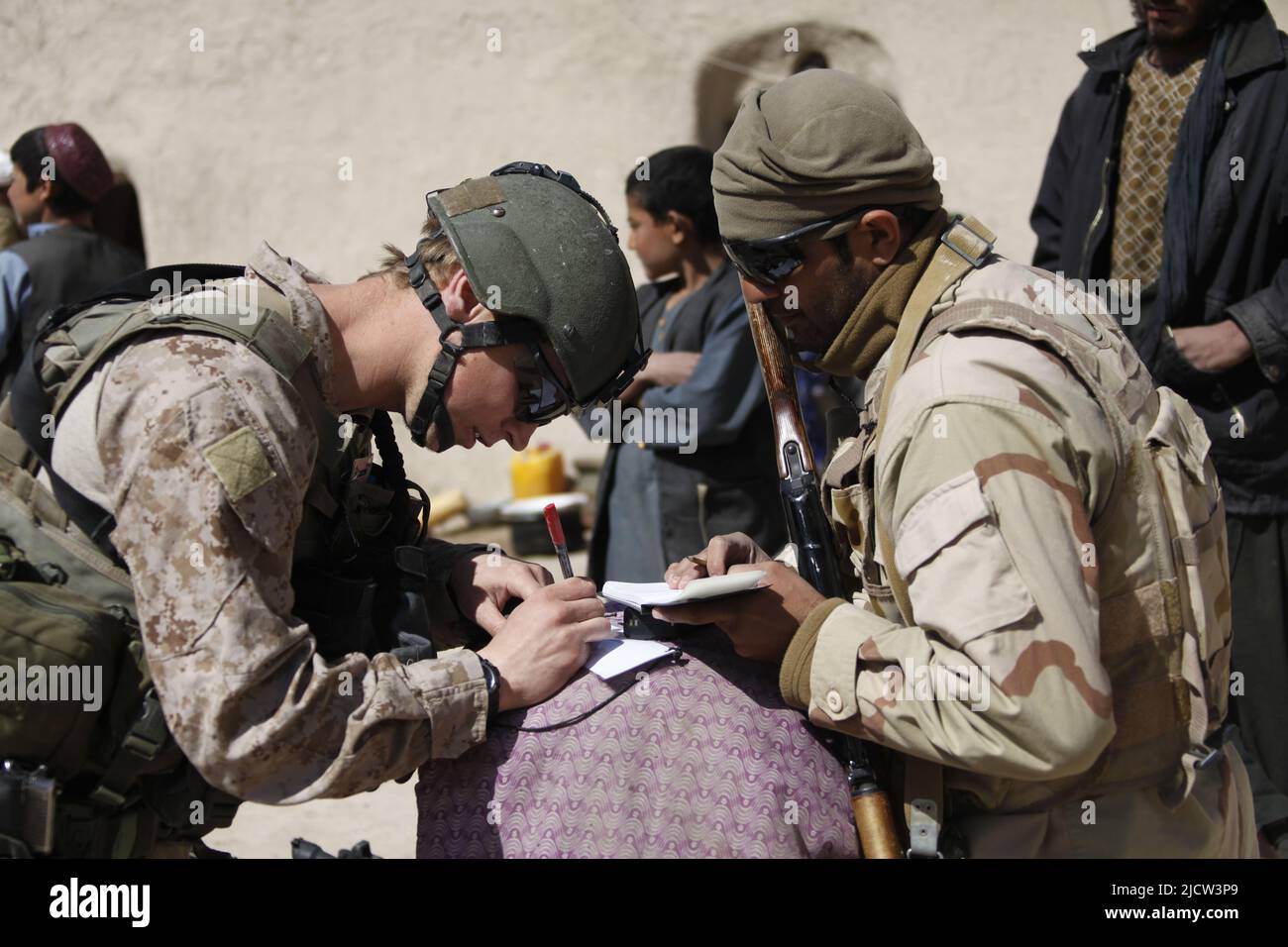 British Royal Marine Commando Lance Cpl. Alan Cahill (left) writes down ...