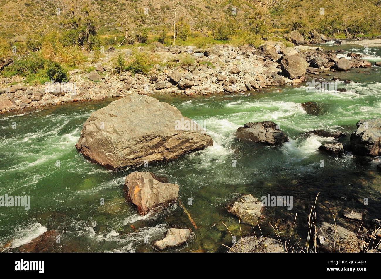 A turbulent stream of a beautiful turquoise river flows in its channel ...
