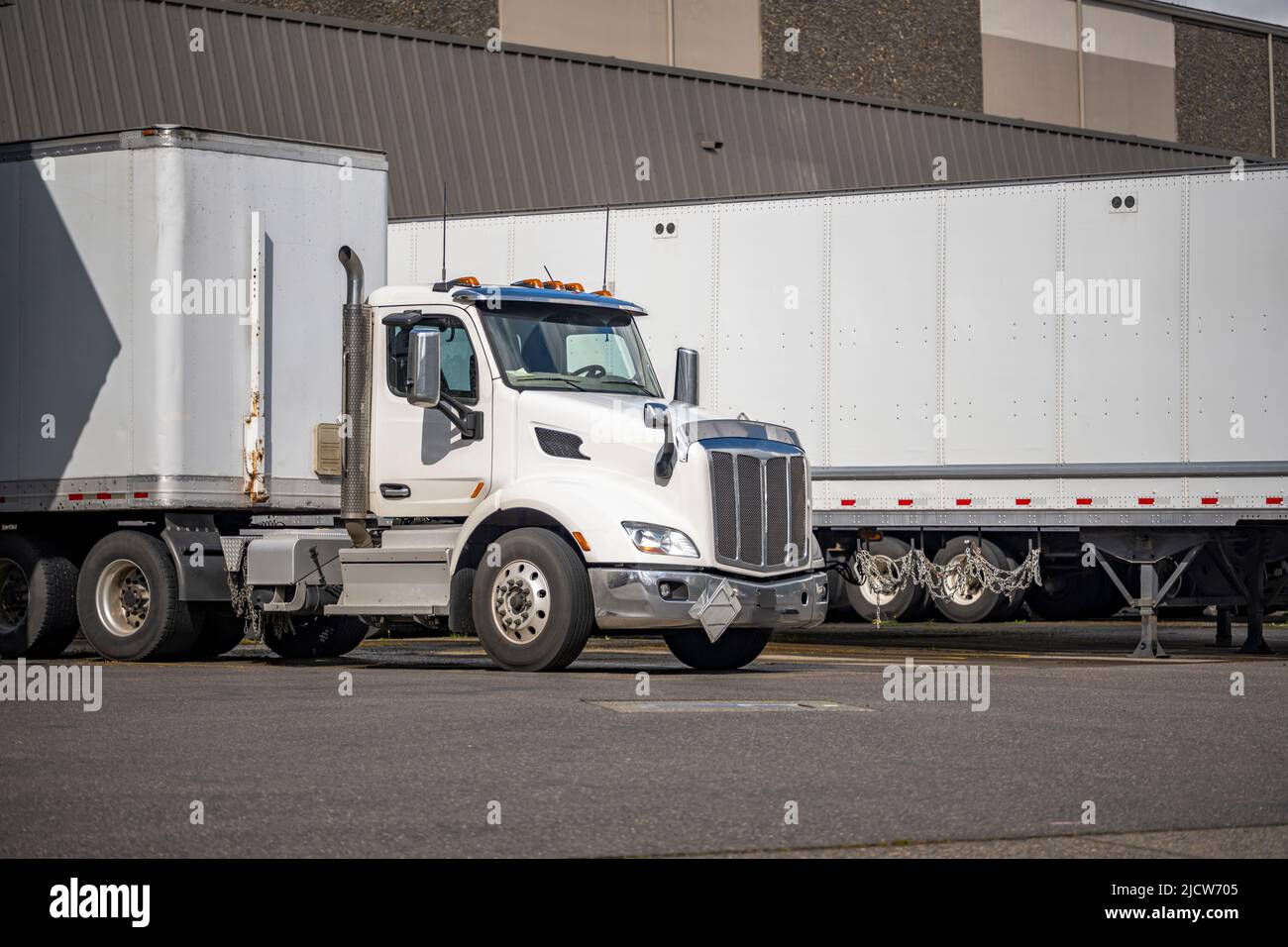 Big rig day cab white semi truck with dry van semi trailer in row with ...