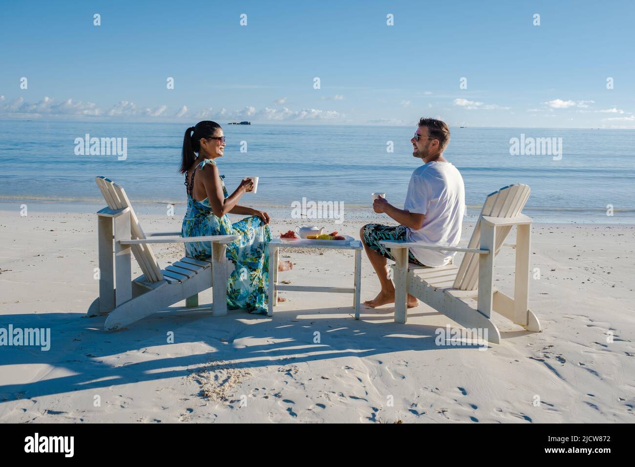 couple men and women on the beach having coffee and fruit for breakfast ...