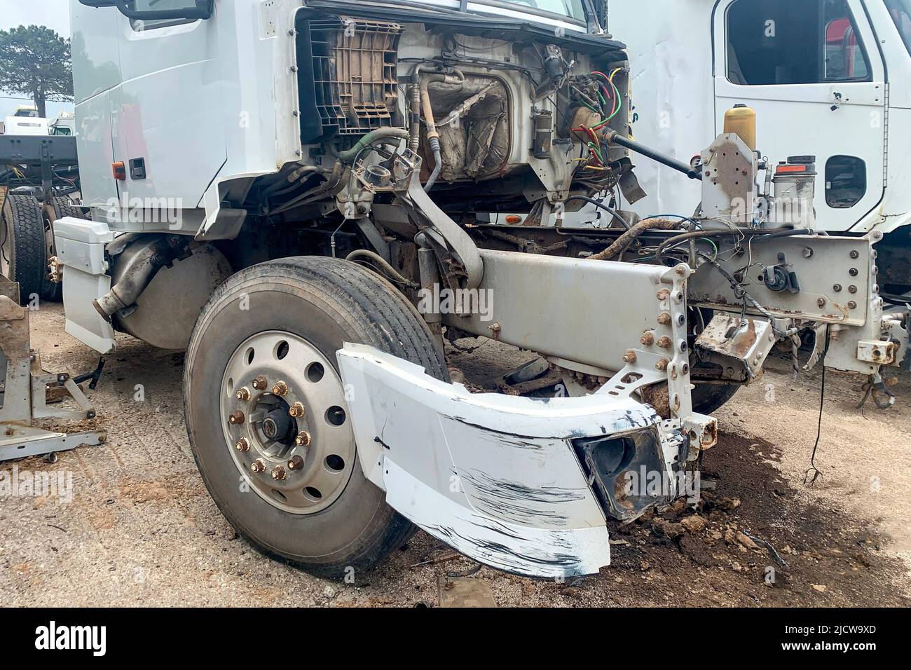 An abandoned truck in a junkyard, a white lorry with a destroyed engine ...