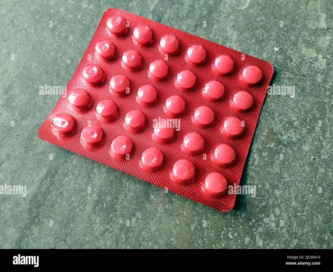 red color medicin pill isolated on stone background Stock Photo - Alamy