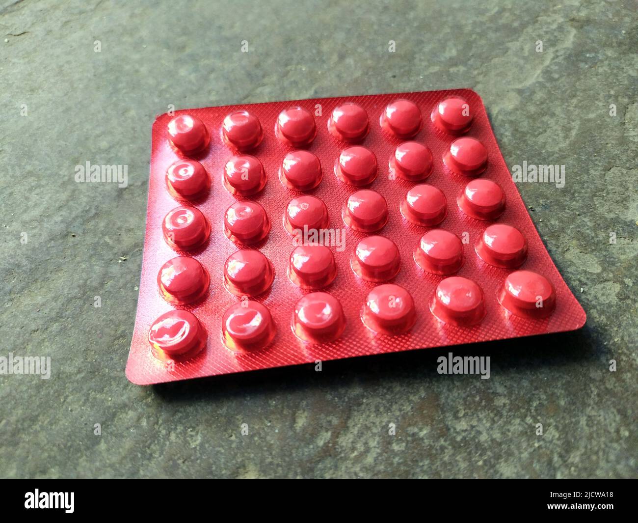 red color medicin pill isolated on stone background Stock Photo - Alamy
